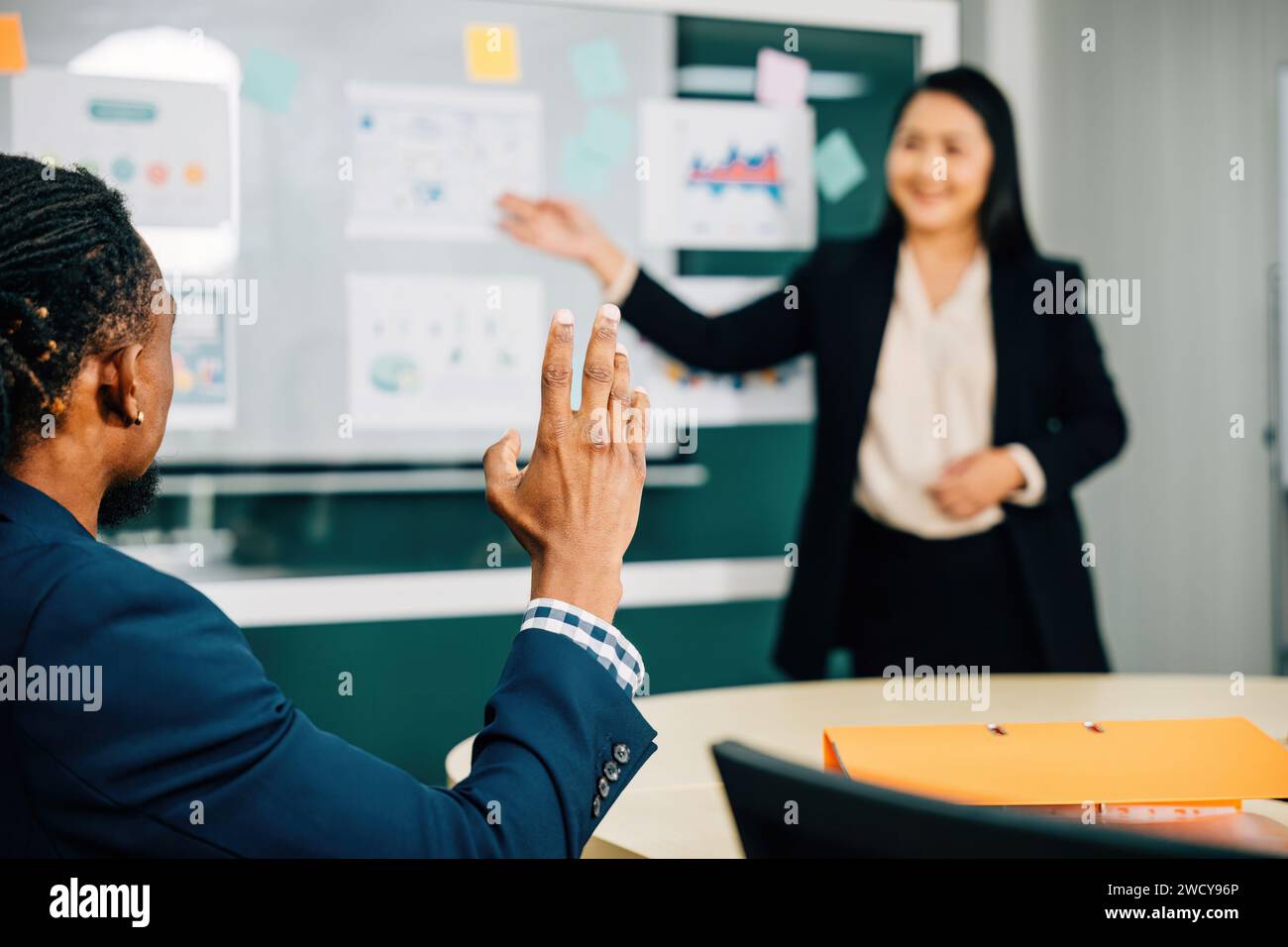 Diverse audience in meeting room raises their hands as exclusive ...