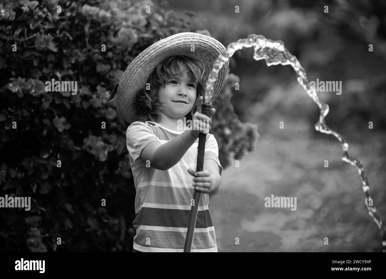 Happy little boy having fun in domestic garden. Child hold watering ...