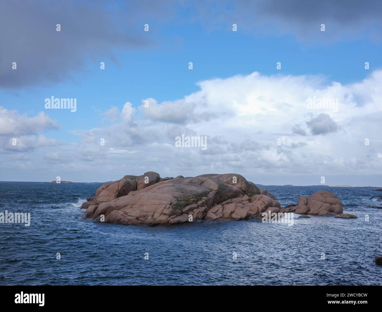Large granite rock island in the Atlantic ocean with clouds and blue ...