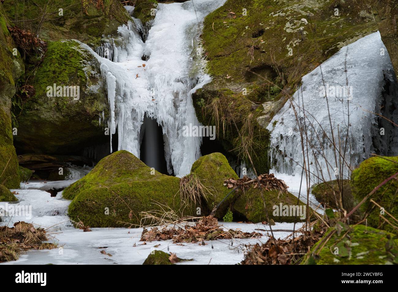 A scenic waterfall cascading over icy rocks with snow and ice ...