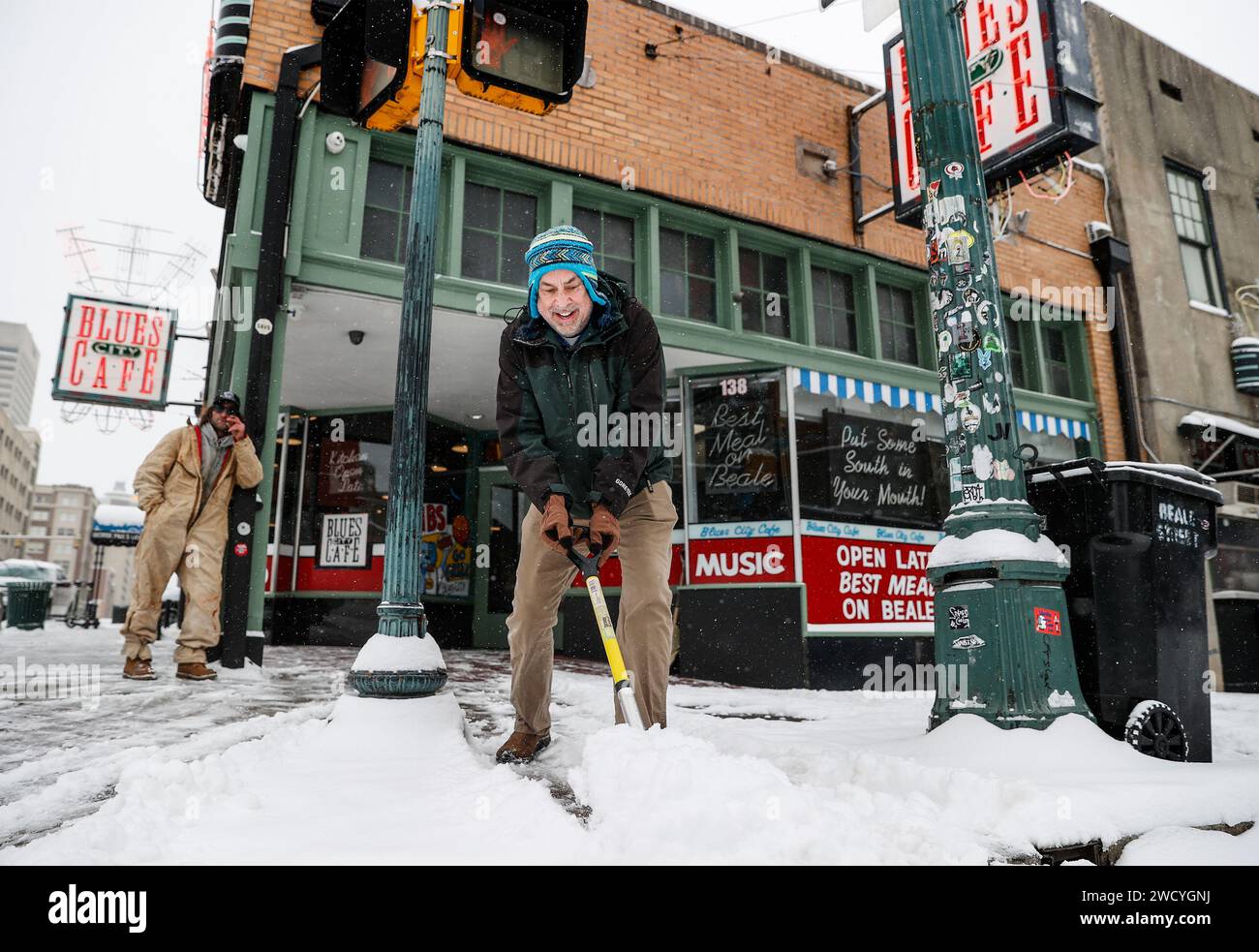 Ken Whitehead clears the sidewalk outside Blues City Cafe as snow falls ...