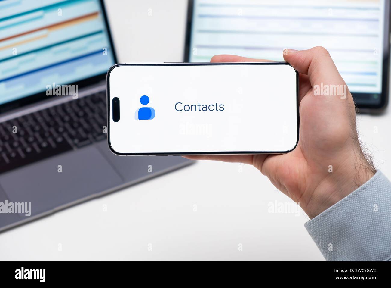 Contacts logo of app on the screen of mobile phone held by man in front ...