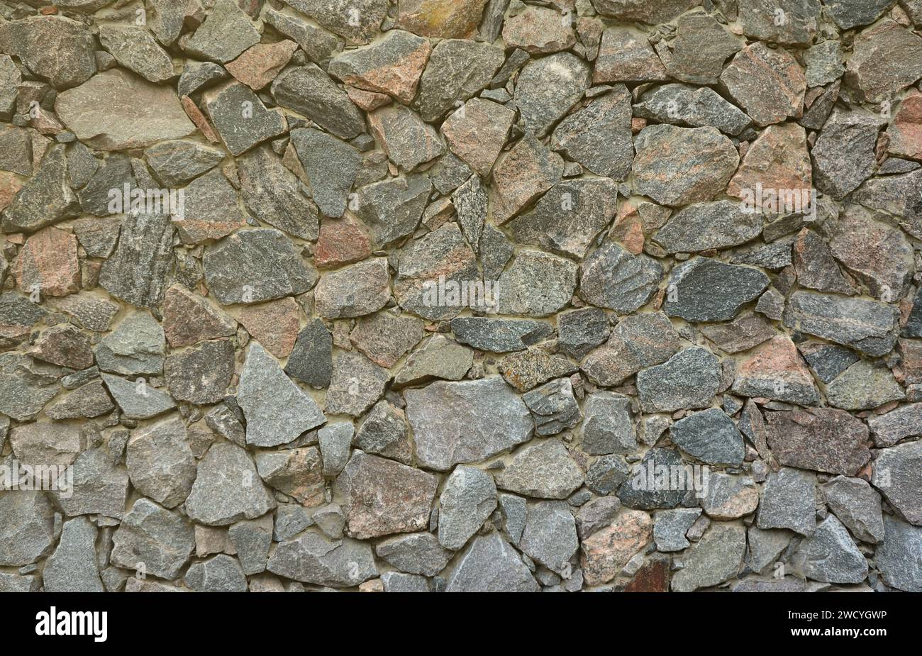 The texture of a strong stone wall of many concreted stones of various ...