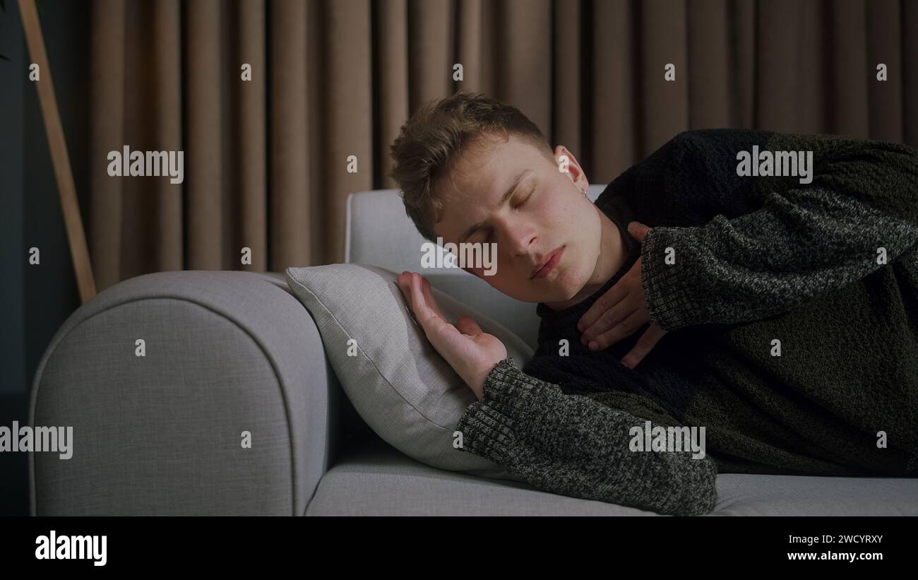 Side shot of blonde man suddenly wakes up while sleeping on sofa at ... Side shot of blonde man suddenly wakes up while sleeping on sofa at ...