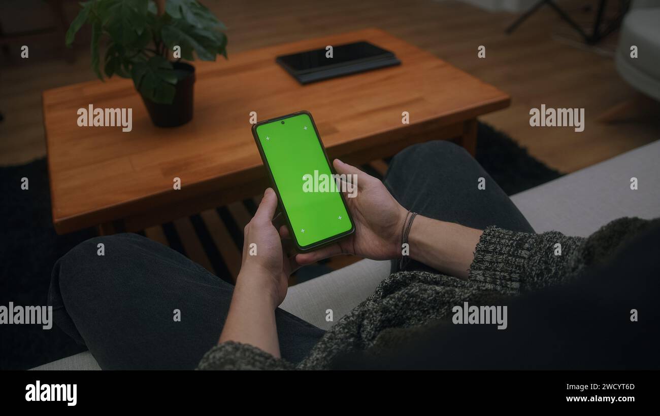 Young man using, tapping on screen smartphone with green mock-up screen ...
