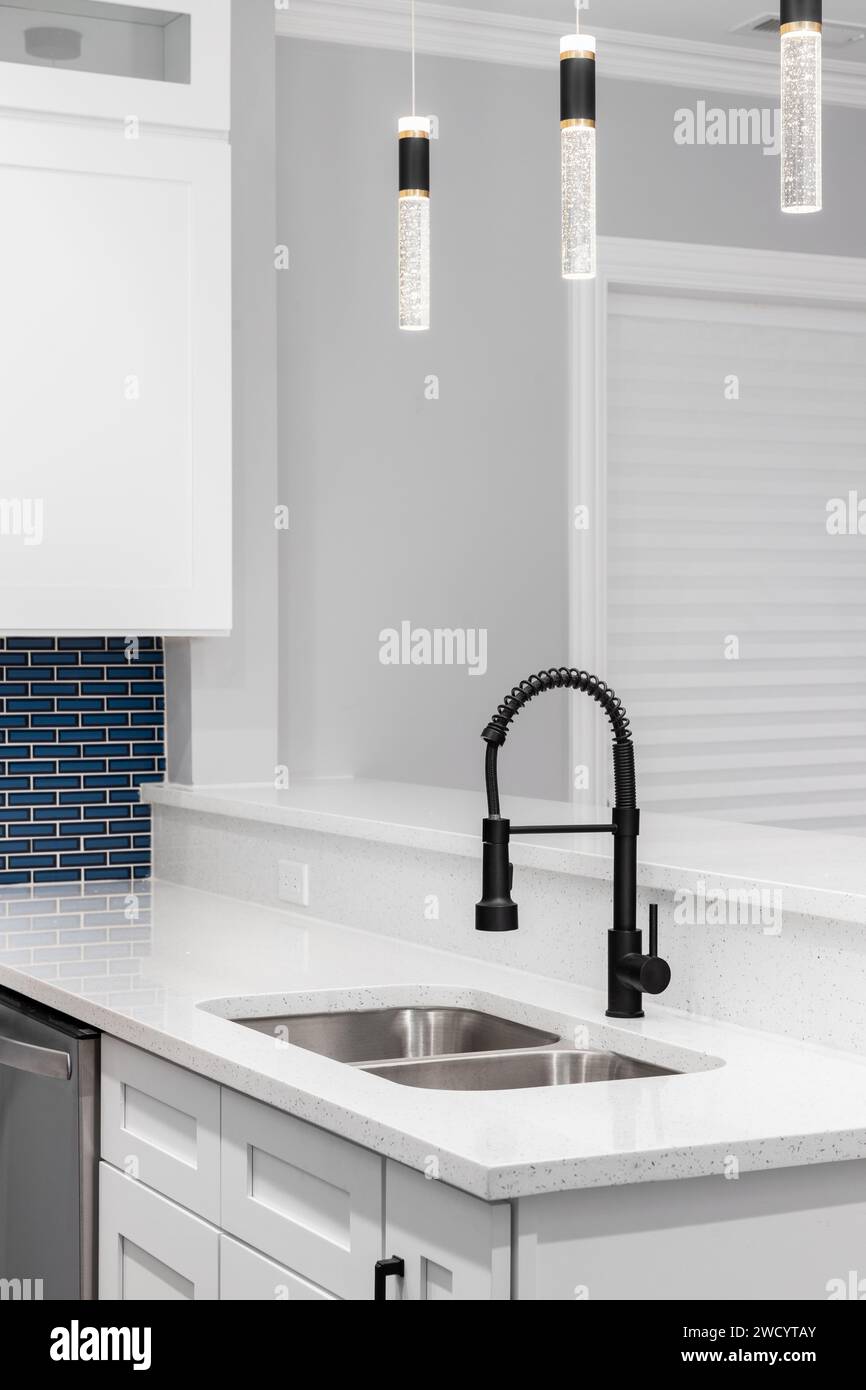 A kitchen detail with a black faucet, glass light fixtures hanging ...