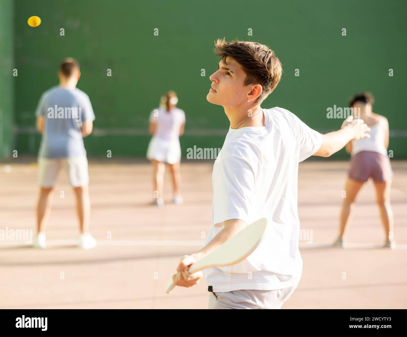 Concentrated young man paleta fronton player hitting ball with racket ...