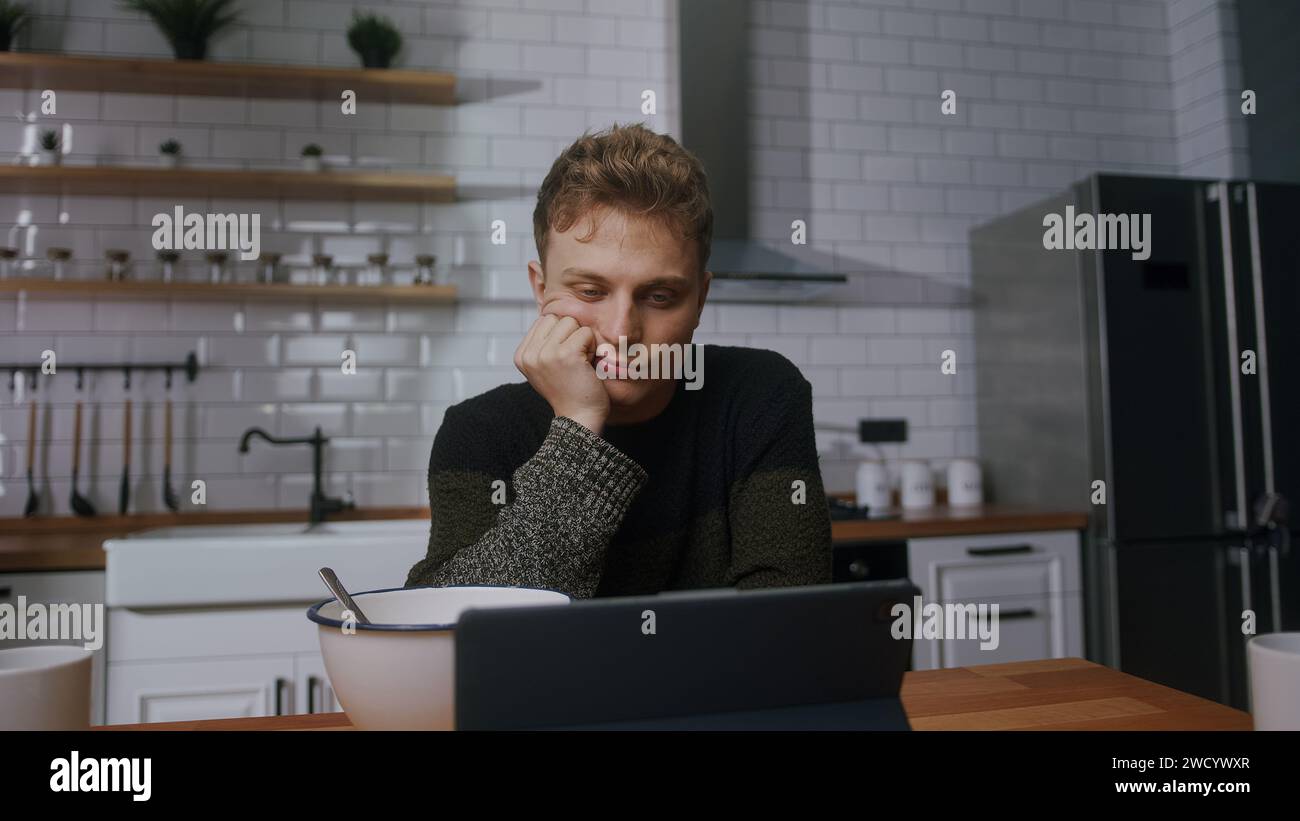 Bored man reluctant to eat pushing a bowl full of cereal while sitting ...