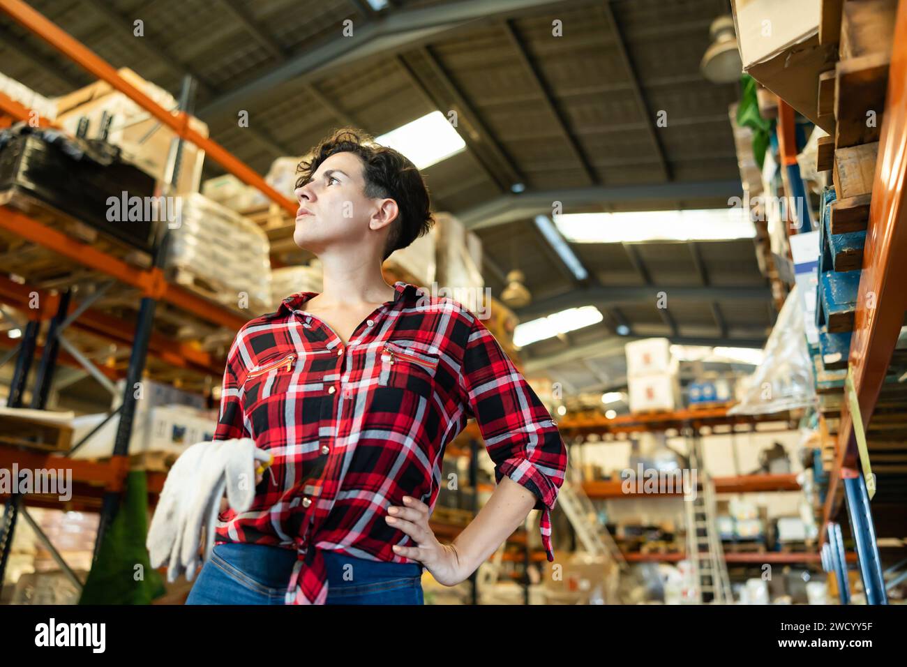 Thoughtful female storekeeper looking for tedious goods in building ...