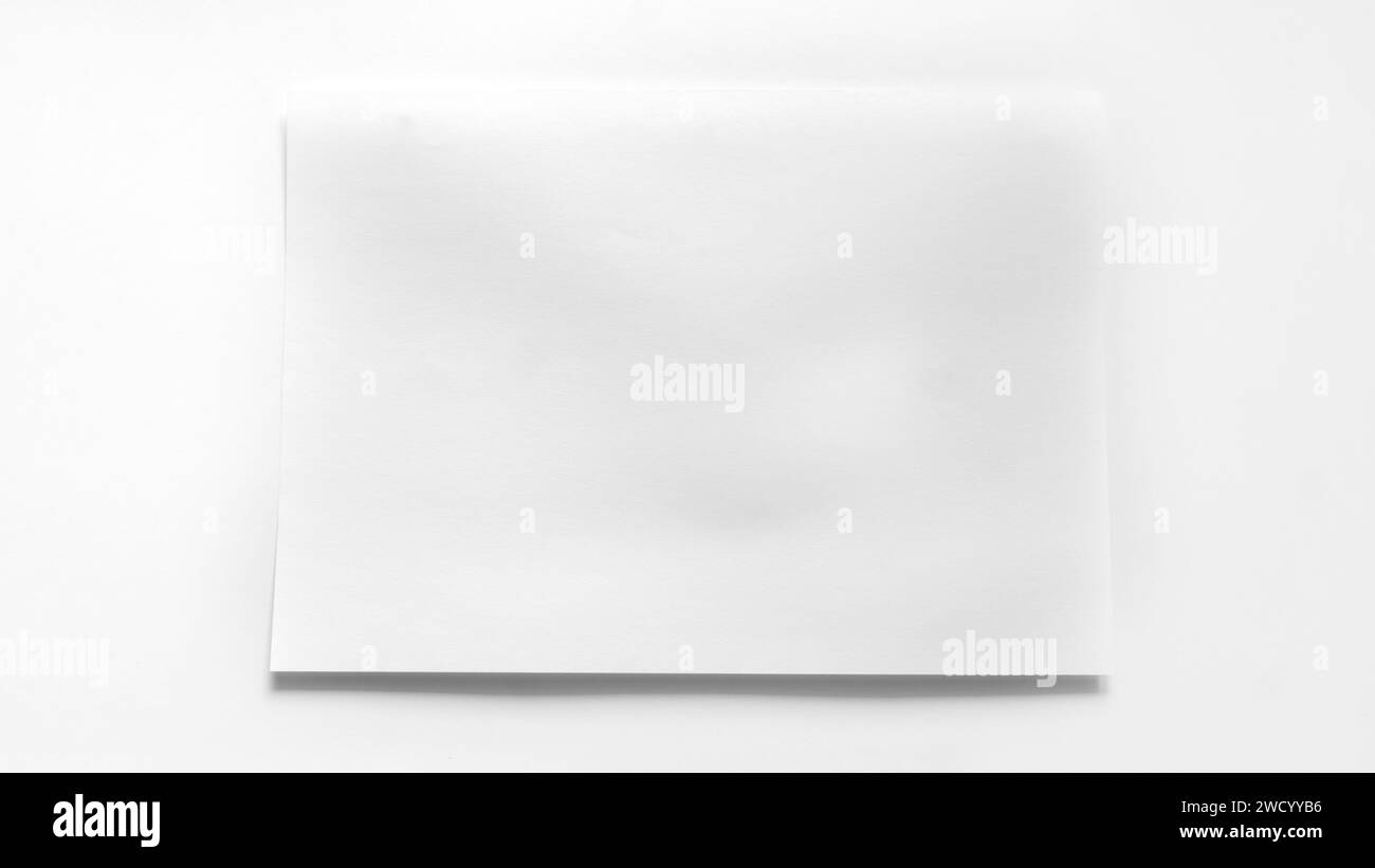 A white, flat sheet of white paper lies on a white background. White ...