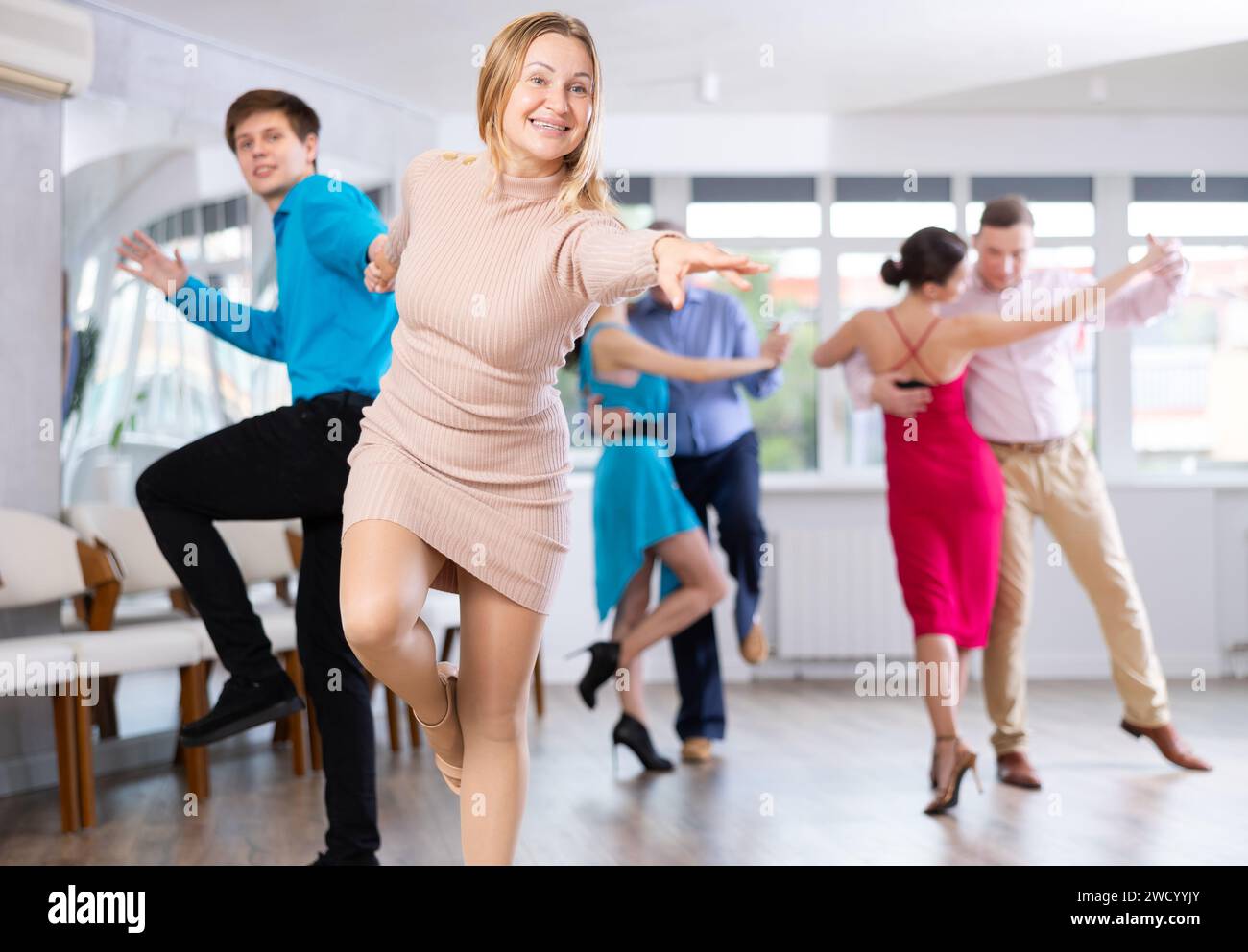 Group is of different ages active people engaged in Latin dance studio ...