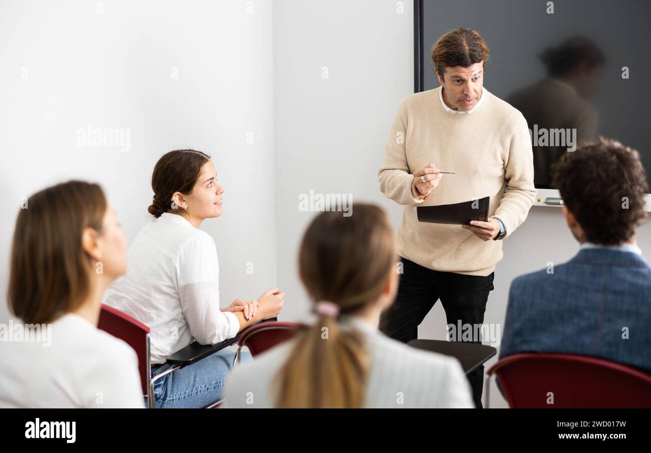 Experienced male teacher giving lecture to group of student Stock Photo ...
