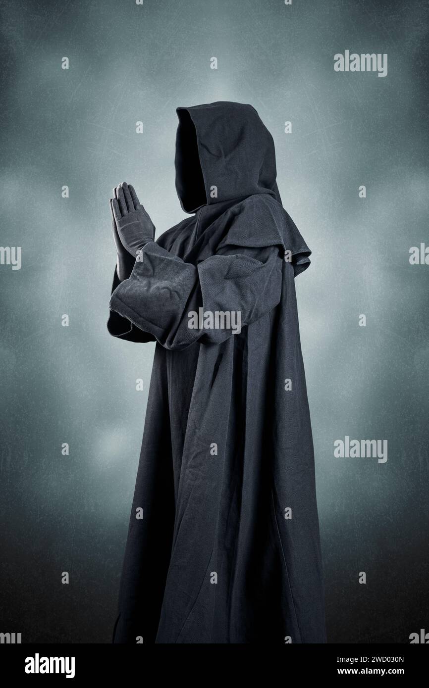 Medieval monk in hooded cloak praying in the dark Stock Photo - Alamy