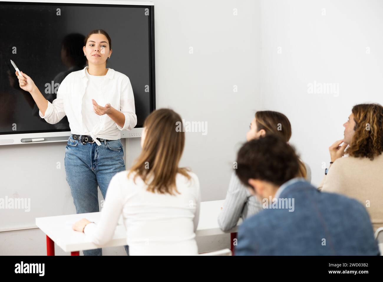 Positive female trainer standing near interactive board and conducting ...