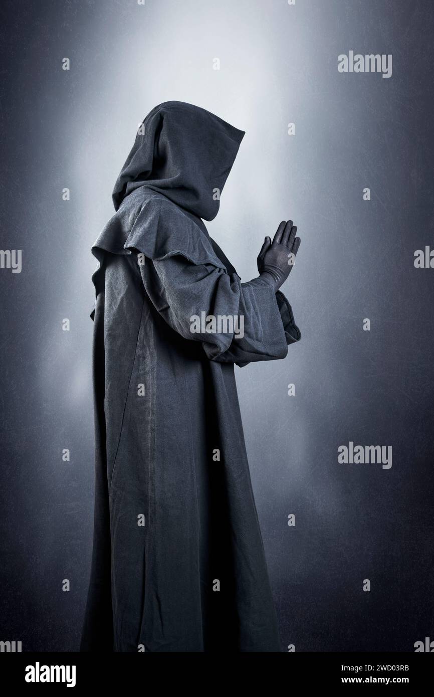 Medieval monk in hooded cloak praying in the dark Stock Photo - Alamy