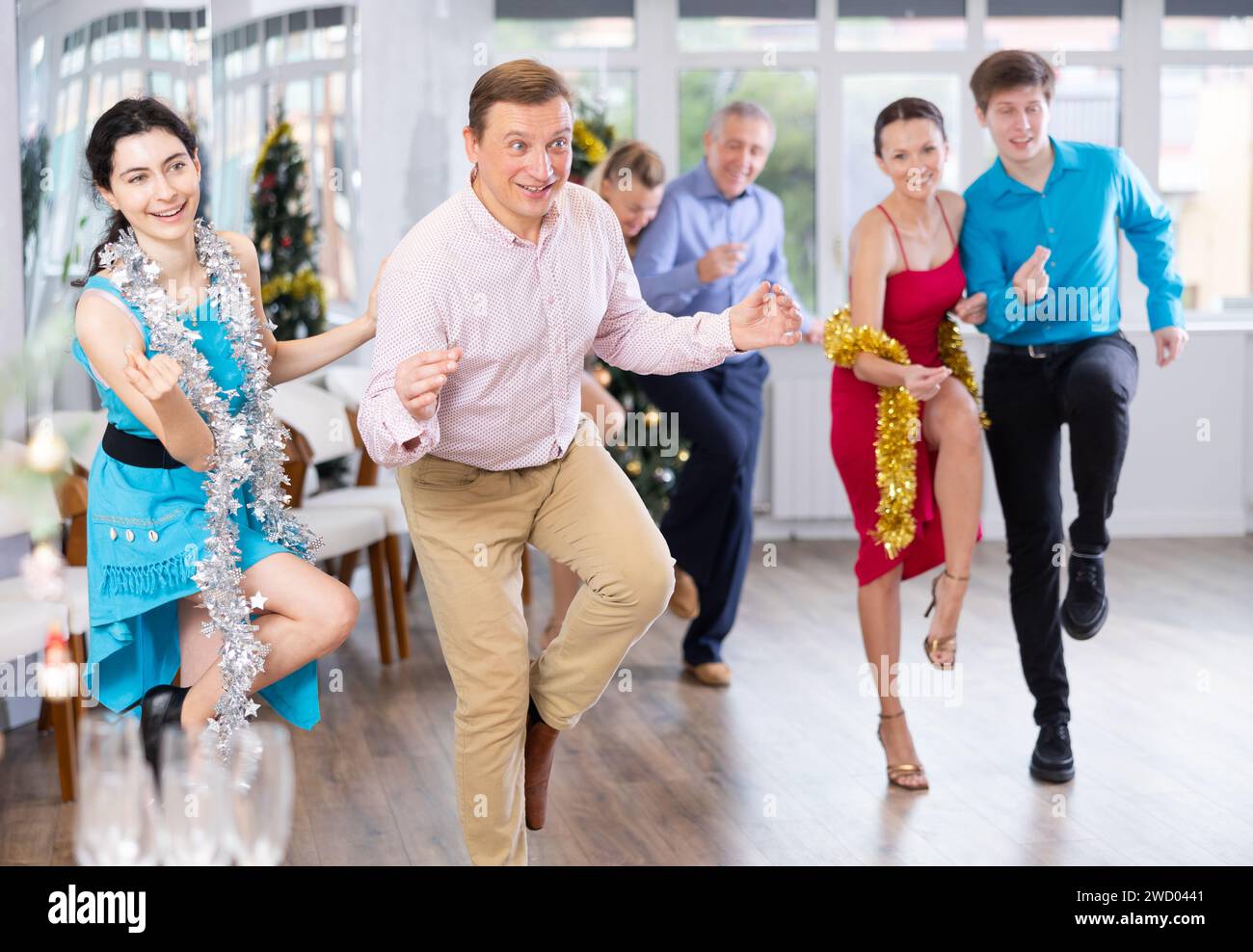 Cheerful man dancing jive with young brunette during corporate ...