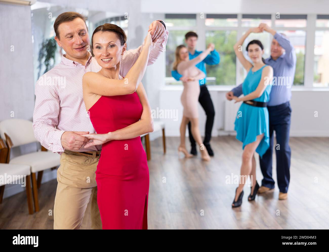 Group of different ages active people in festive clothes dancing dance ...