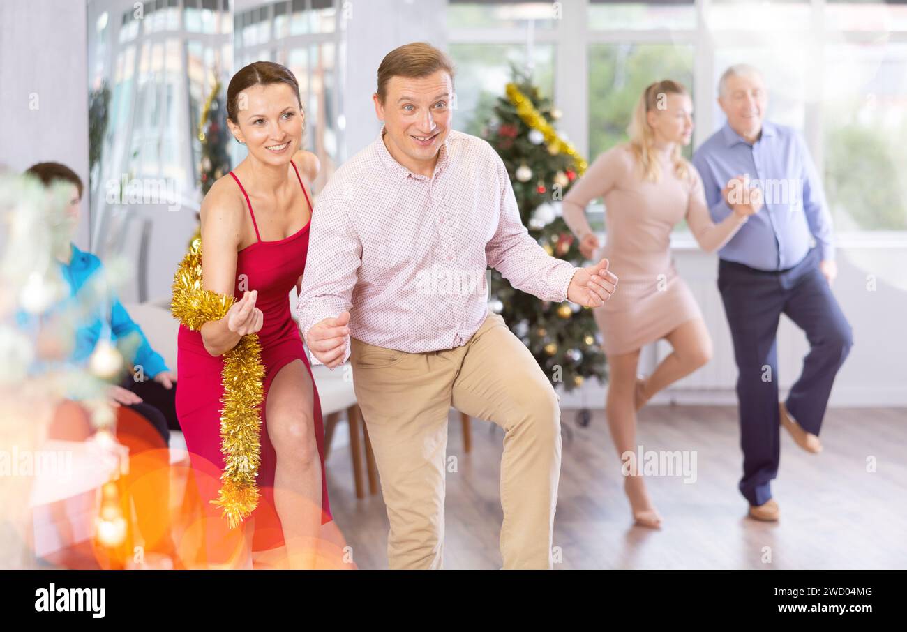 Lively adult couple dancing Lindy Hop at office New Year celebration ...
