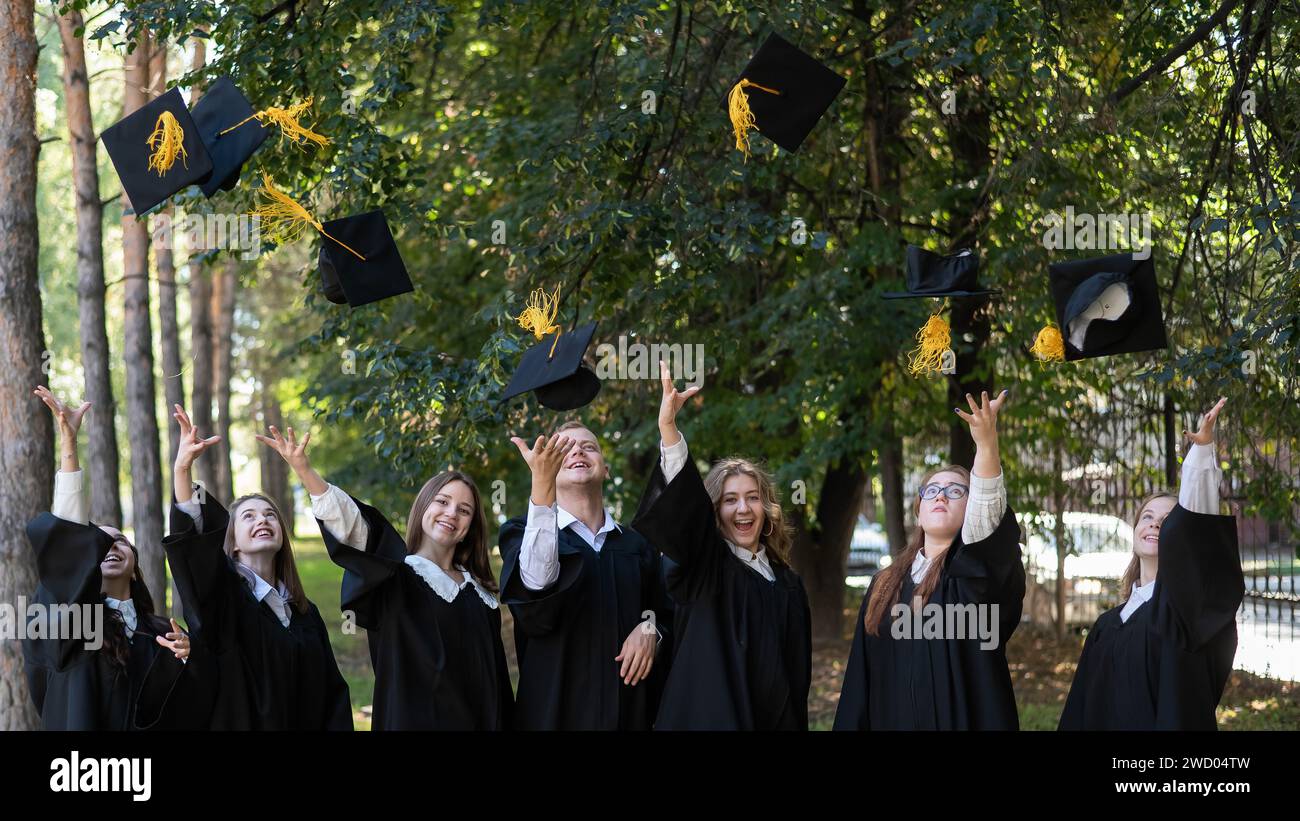 Classmates in graduation gowns throwing hats outdoors Stock Photo - Alamy