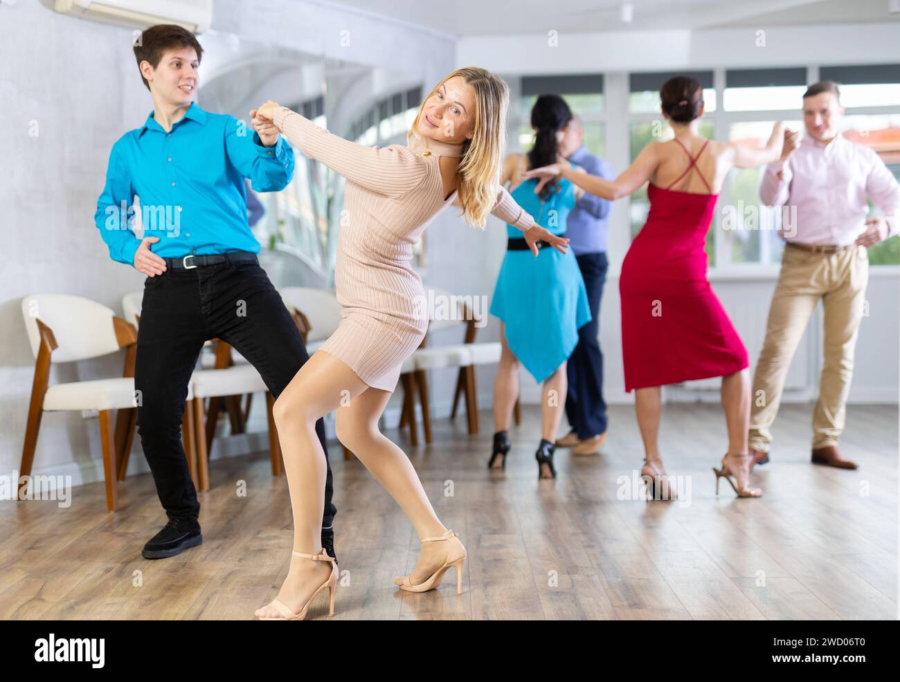 Positive woman enjoying active dances with partner in dance studio ...