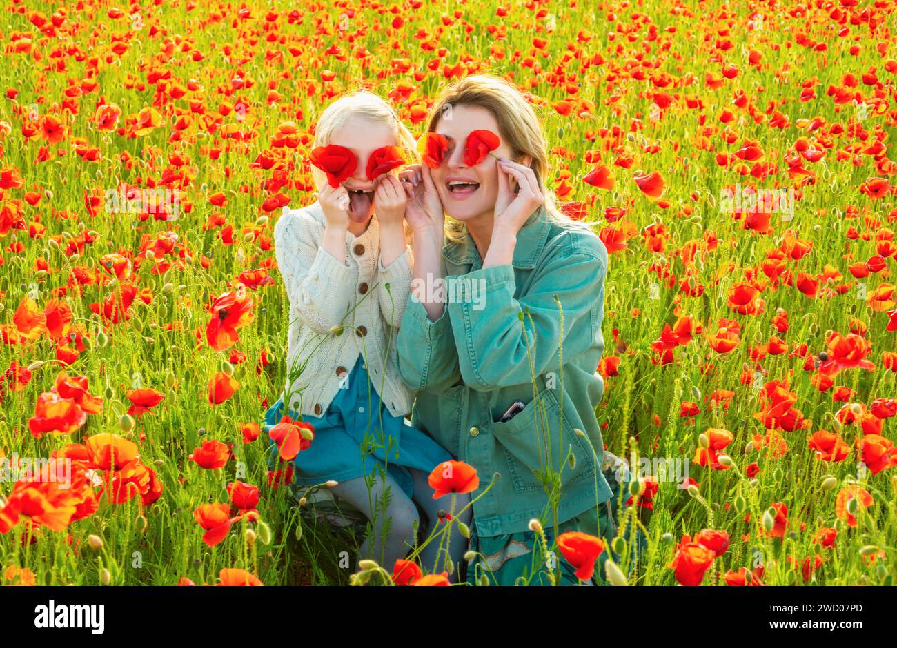 Happy spring family. Mother and daughter hugging in a poppies meadow ...