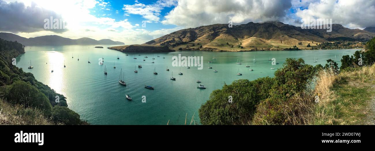 Sail boats sailing and moored in the still ocean between the coastline ...