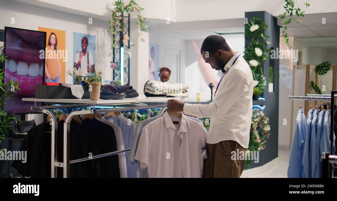 Retail clerk working in luxury fashion boutique, arranging clothes on ...