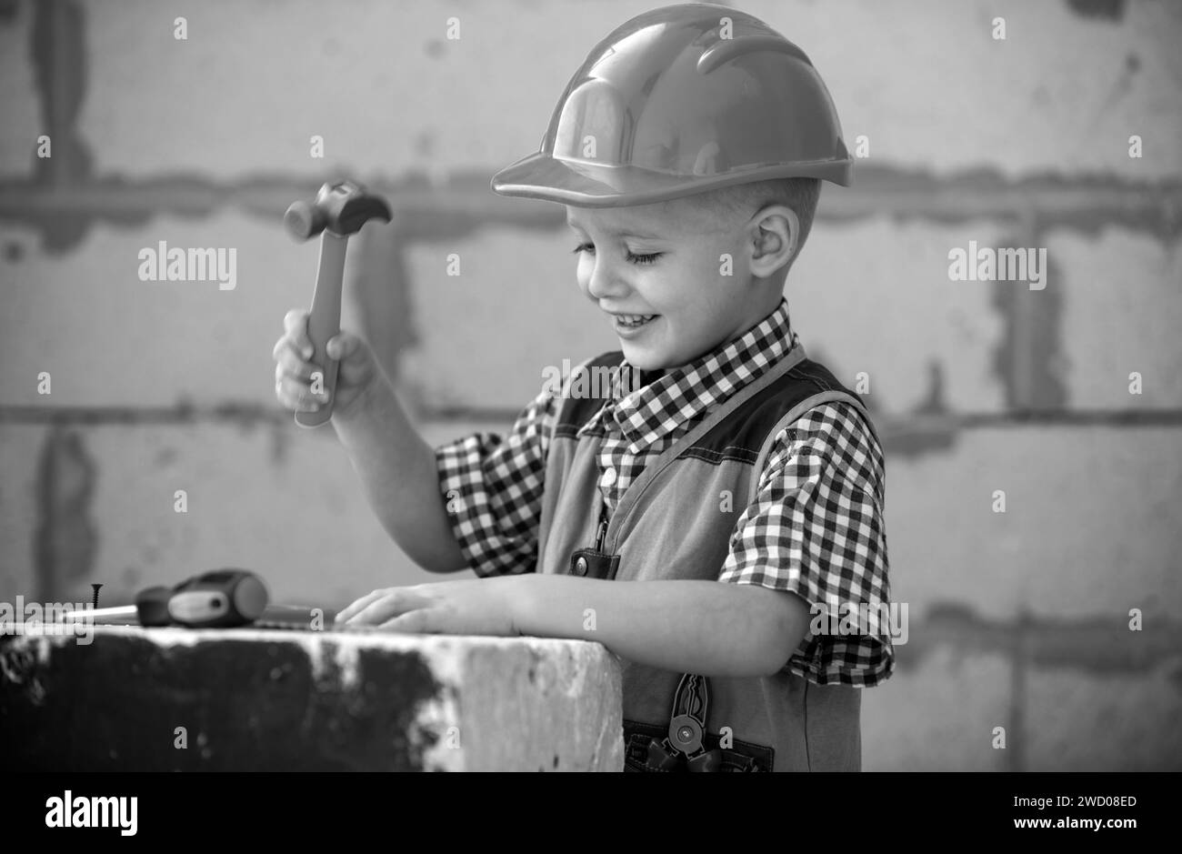 Kid in hard hat holding hammer. Little child helping with toy tools on ...