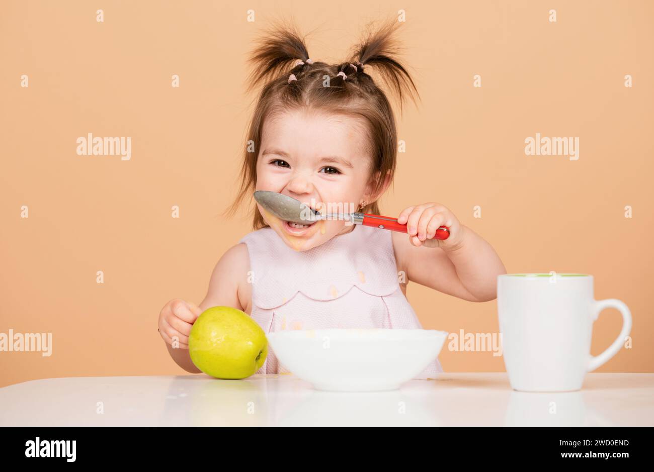 Baby eating kids food. Babys first meal. The child eats on his own with ...