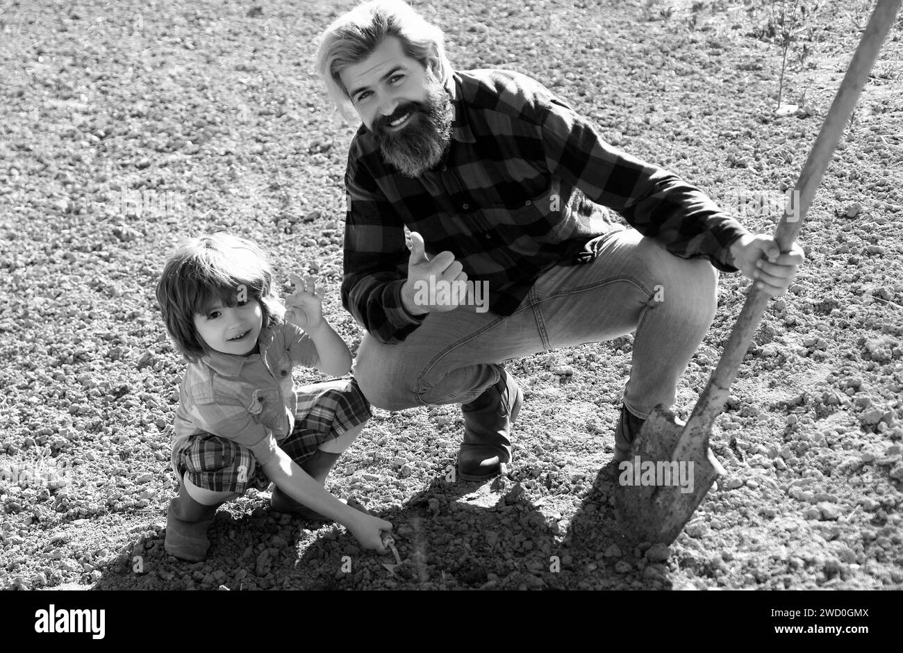 Father planting with helper son. Dad and kid gardening in garden ground ...