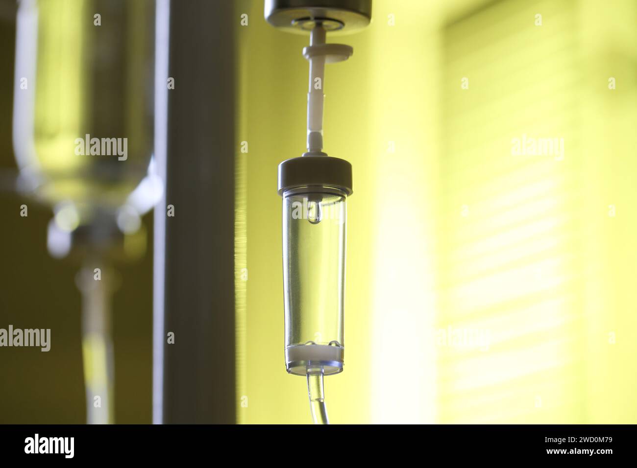 IV drip chamber against blurred yellow background Stock Photo - Alamy