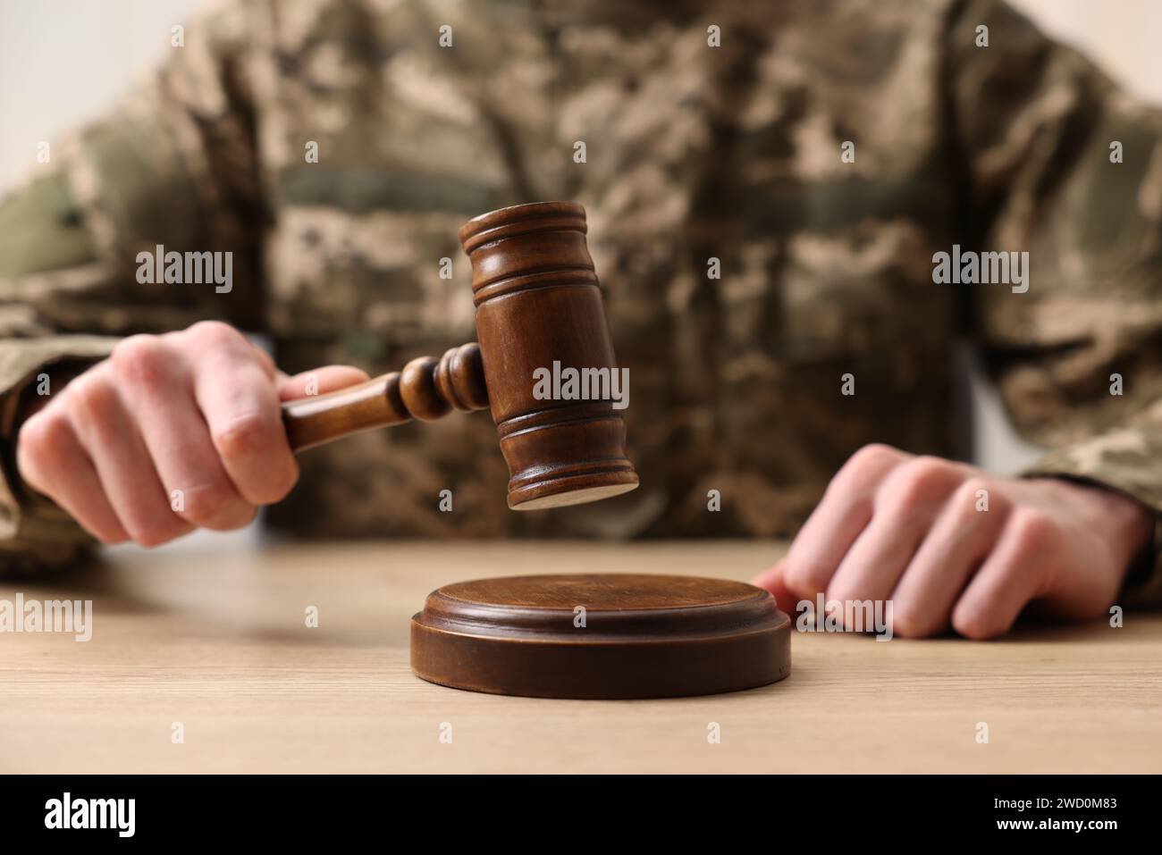 Law concept. Man in military uniform with gavel at wooden table ...