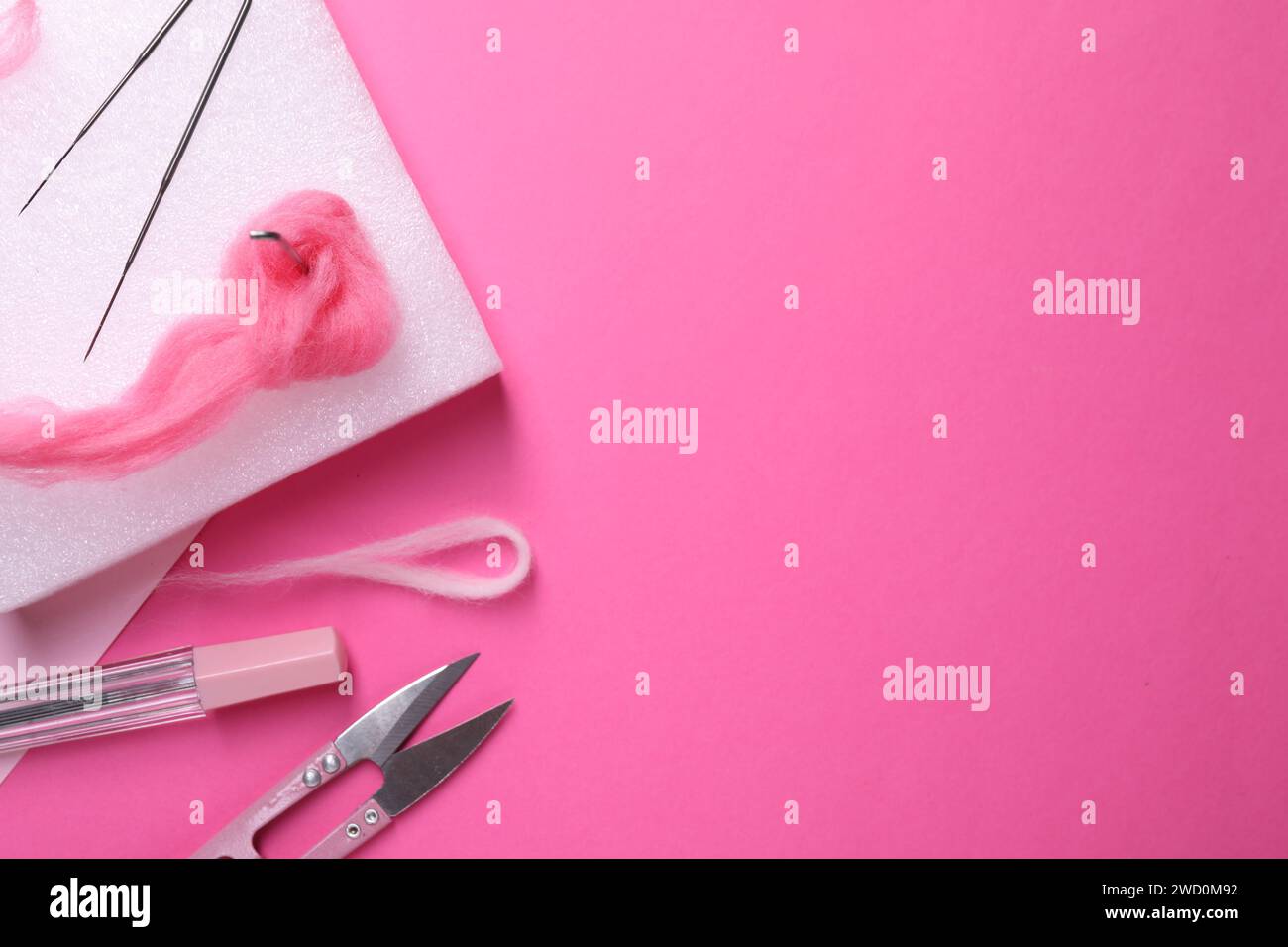 Flat lay composition with wool and needle felting tools on pink ...