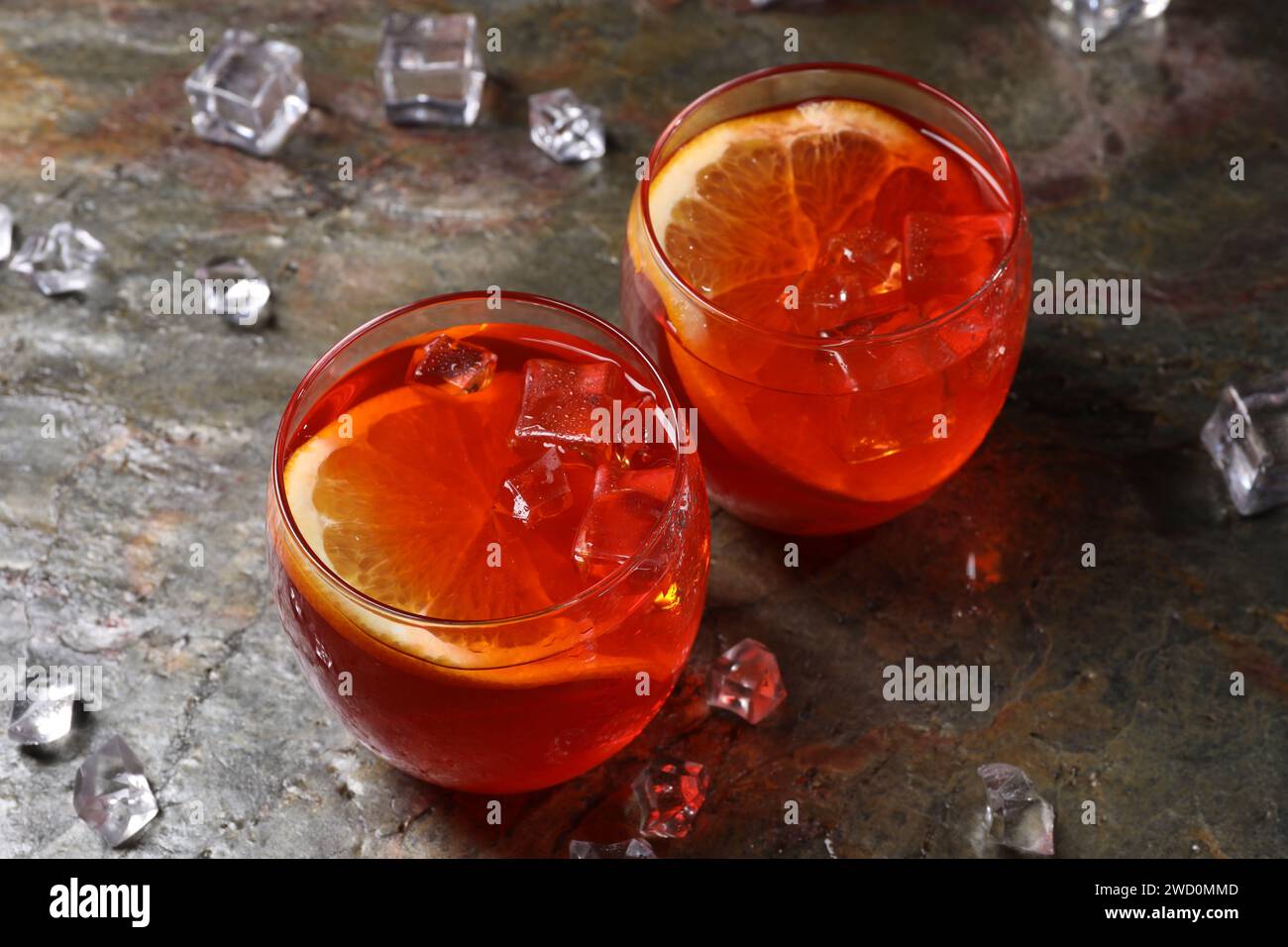 Aperol spritz cocktail, ice cubes and orange slices in glasses on grey ...