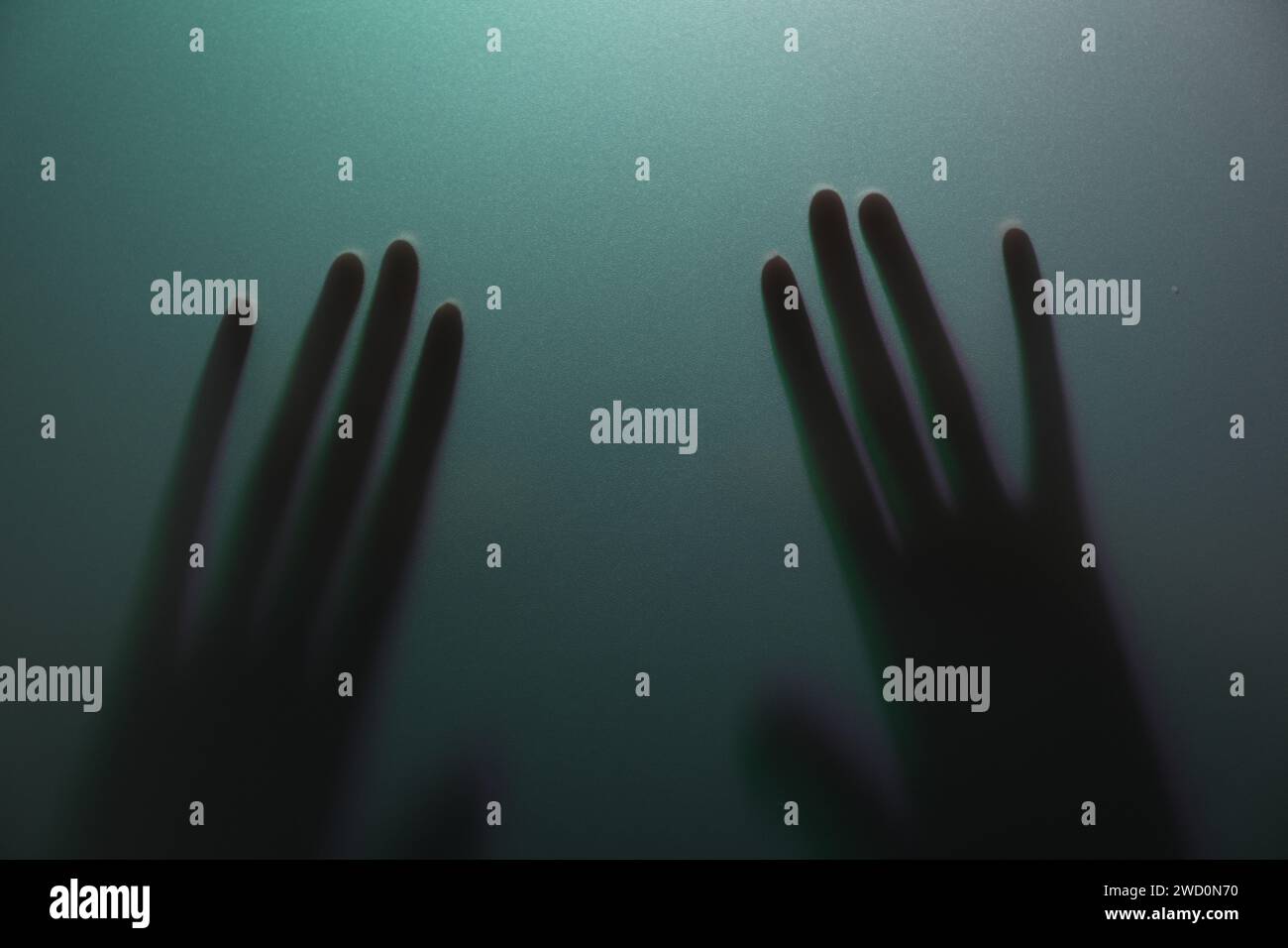 Silhouette of creepy ghost behind glass against color background ...