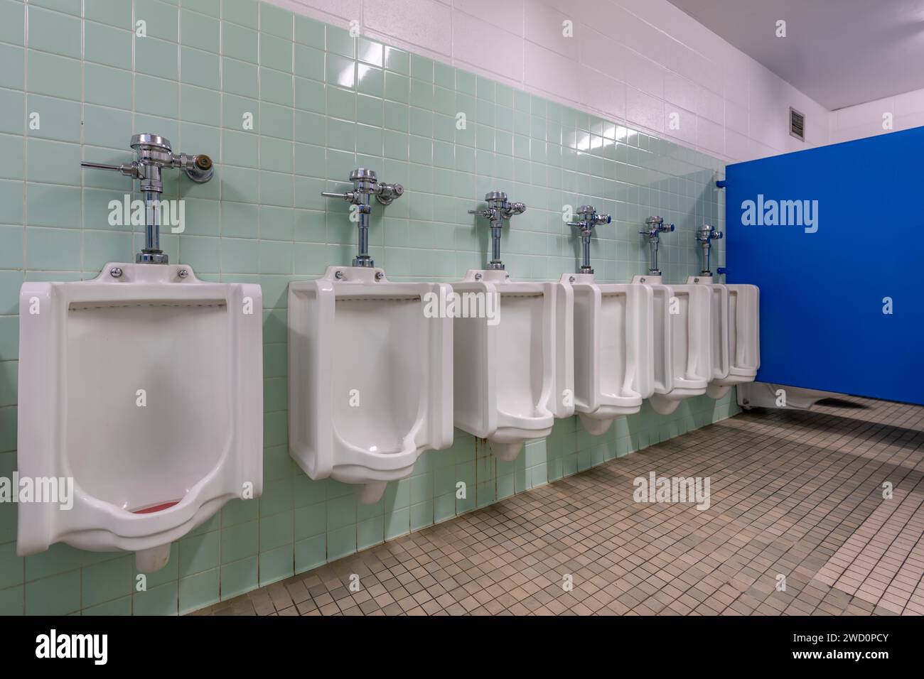Row of multiple white porcelain ceramic urinals in an older men's ...