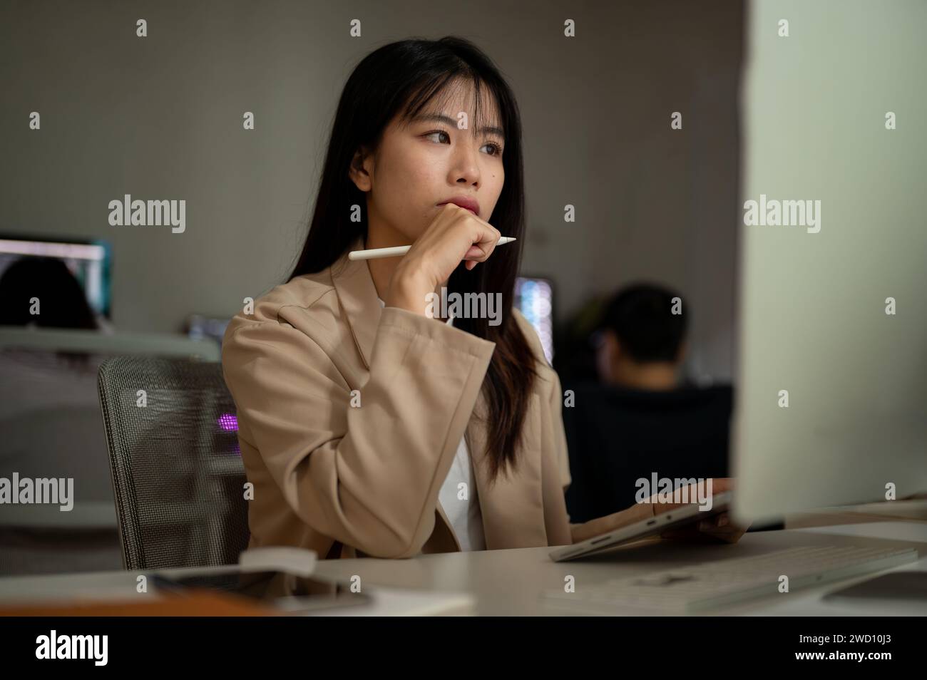 Young concentrated Asian businesswoman or female office employee is ...