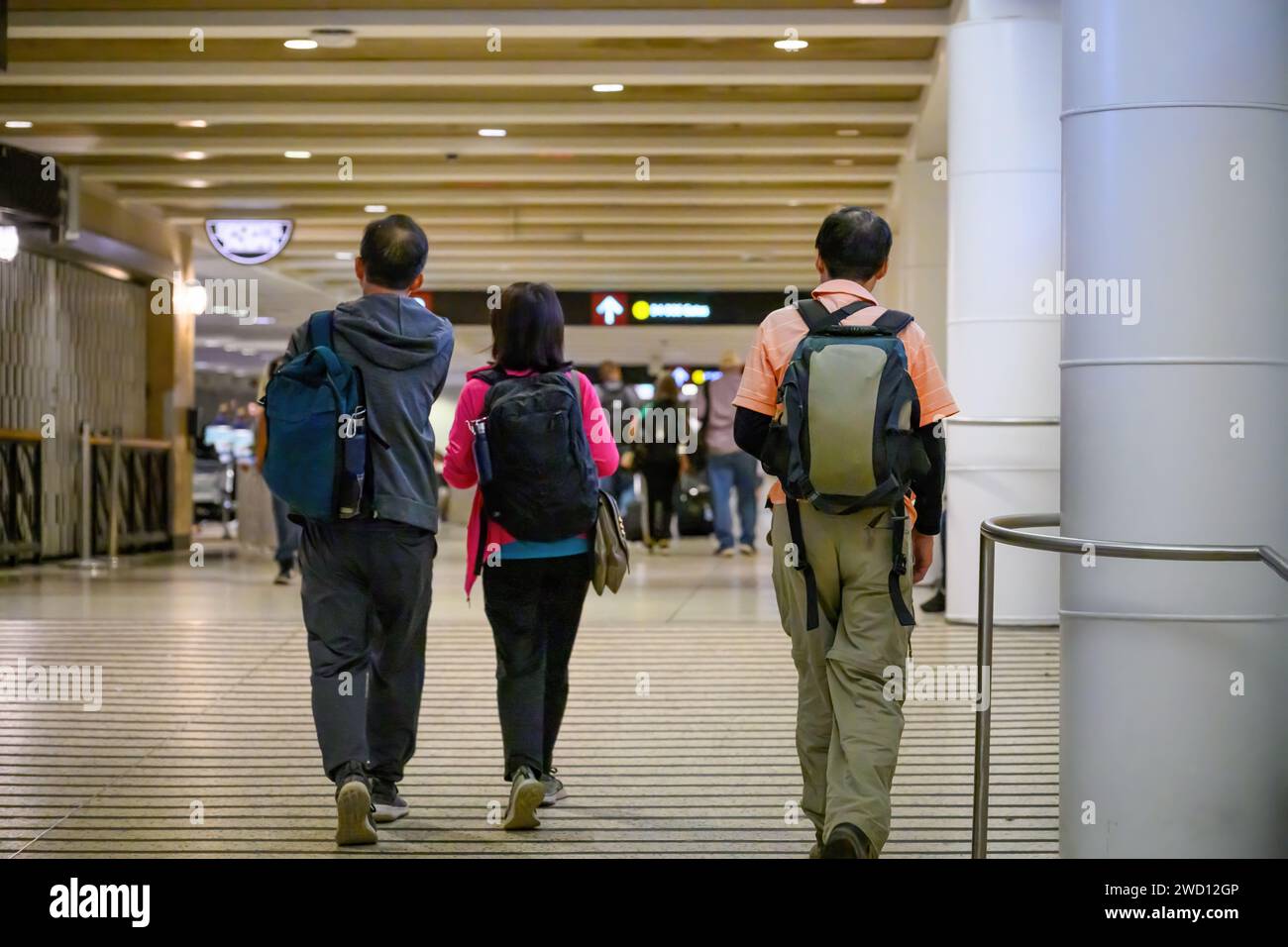 Three people walking in the airport departure area. Unrecognisable ...