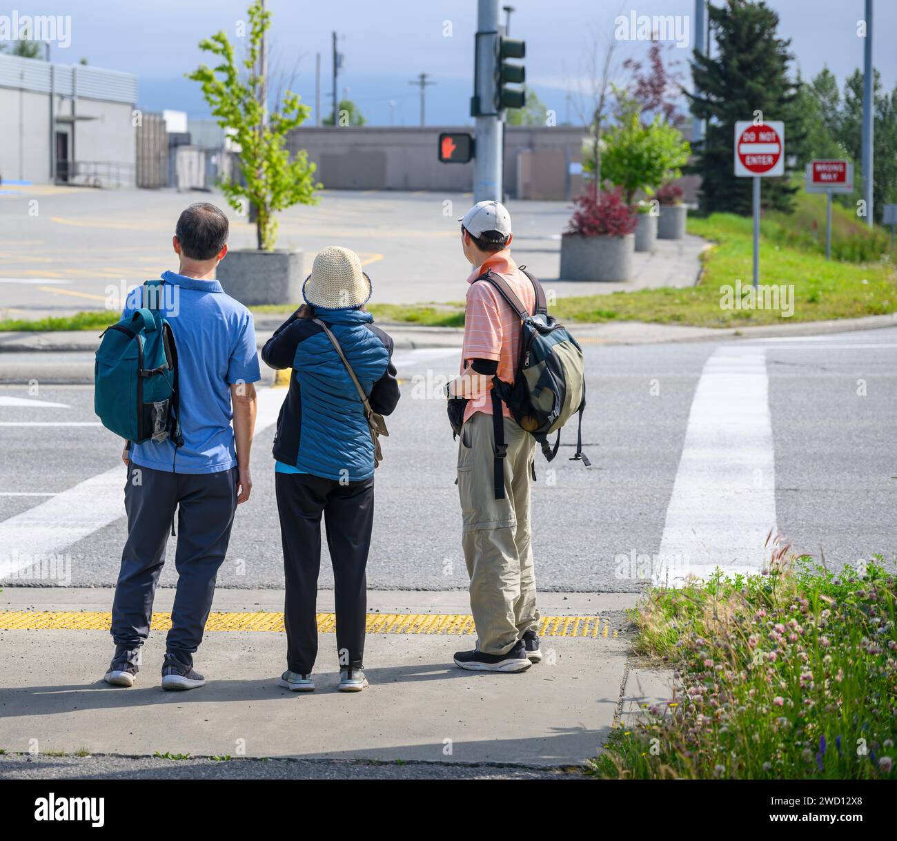Three people waiting at the intersection. Red hand pedestrian stop sign ...