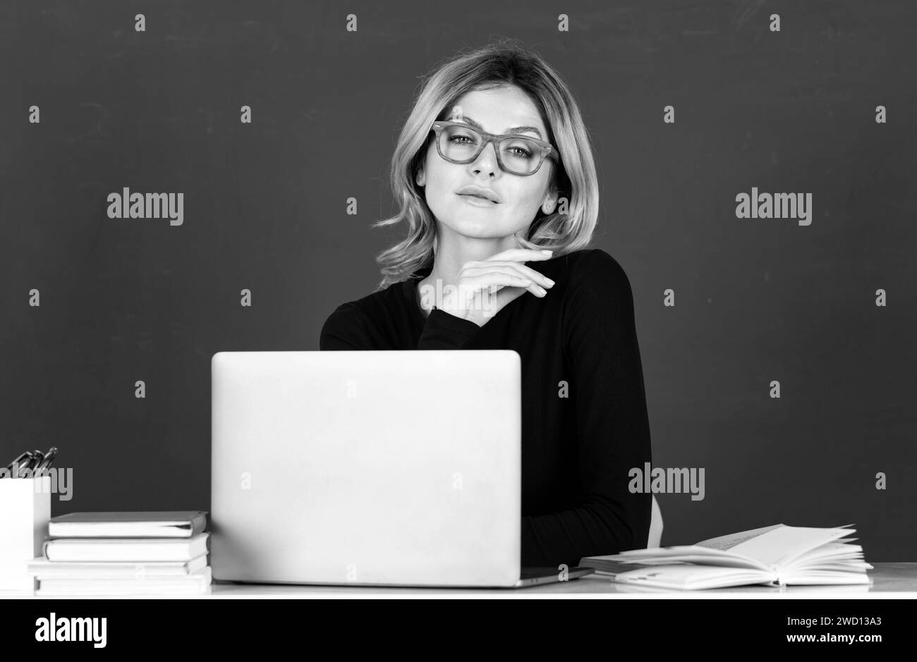 Portrait of teacher or female tutor working at table in school. Young ...