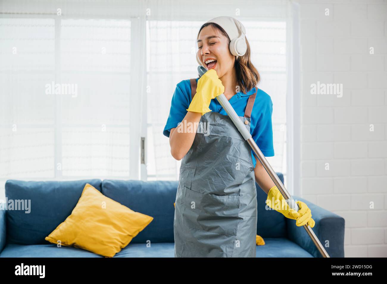 Happy Asian housewife finds joy in cleaning singing her favorite song ...