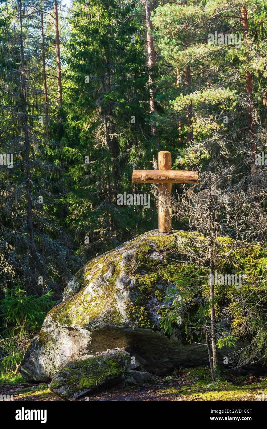 Wooden cross on a stone in forest chapel near Makkarajärvi lake in ...