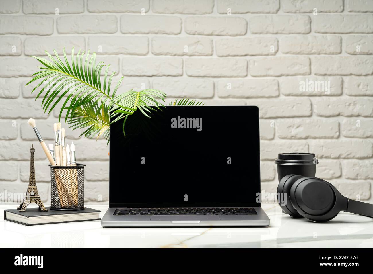Laptop with black screen on desk against white brick wall Stock Photo ...