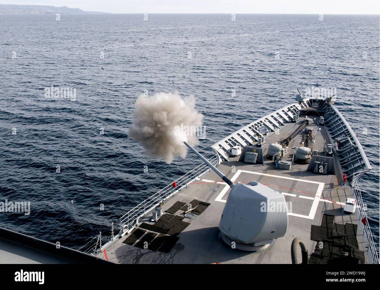 A Mark 45 5-inch gun fires off the port side of guided-missile cruiser ...