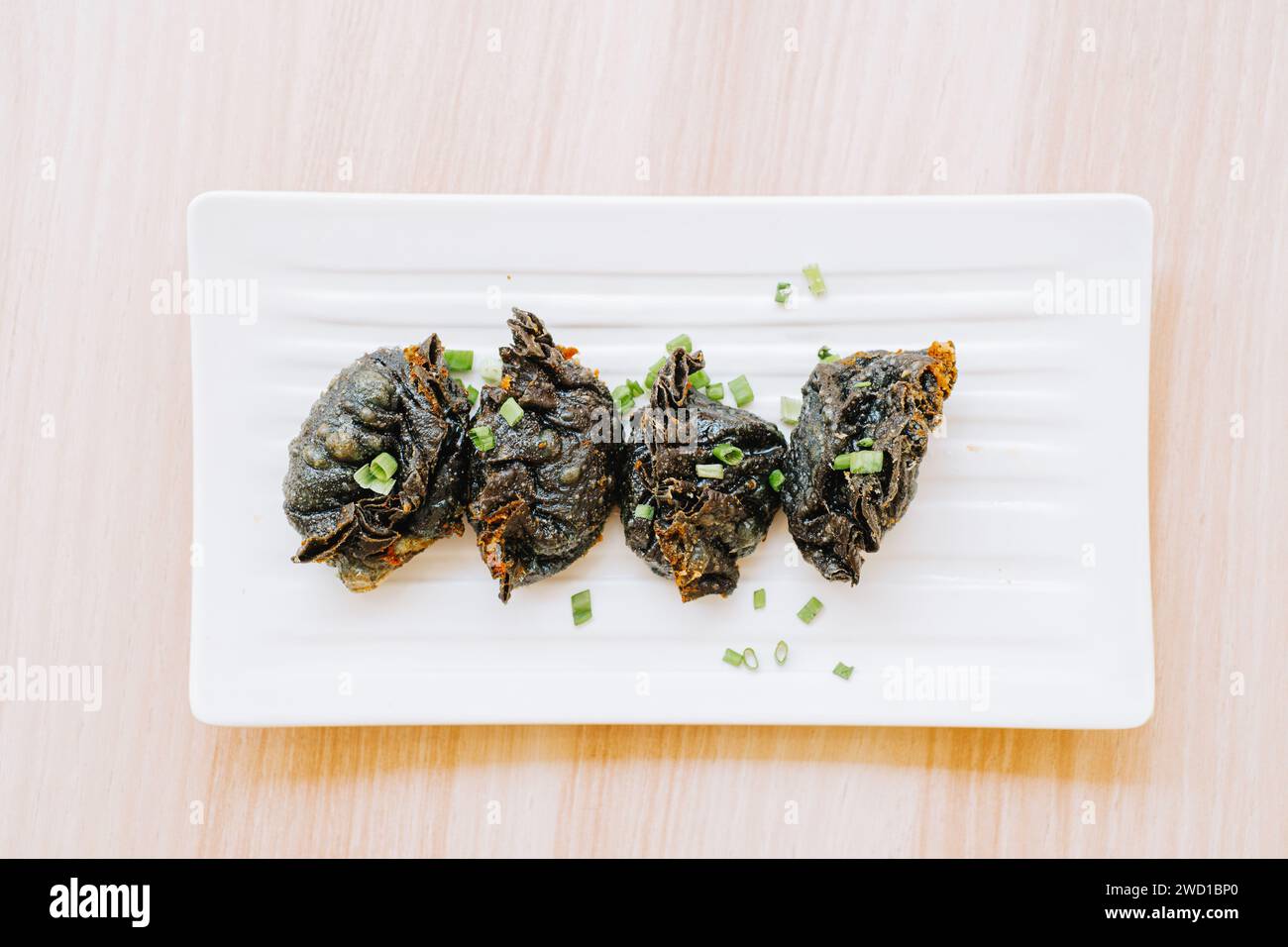 Black Fried Gyoza on a plate on wooden table. Japanese traditional ...