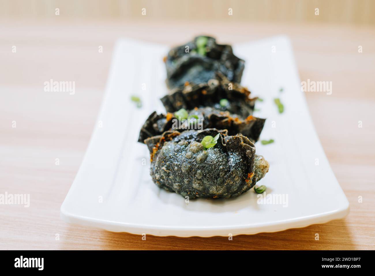 Black Fried Gyoza on a plate on wooden table. Japanese traditional ...