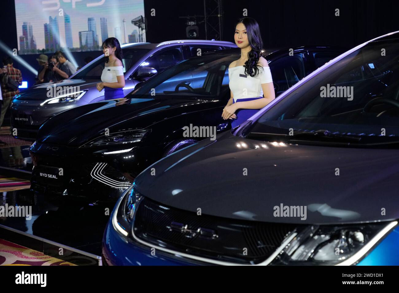 Models stand near BYD electric cars on display, from left, Atto 3, Seal ...