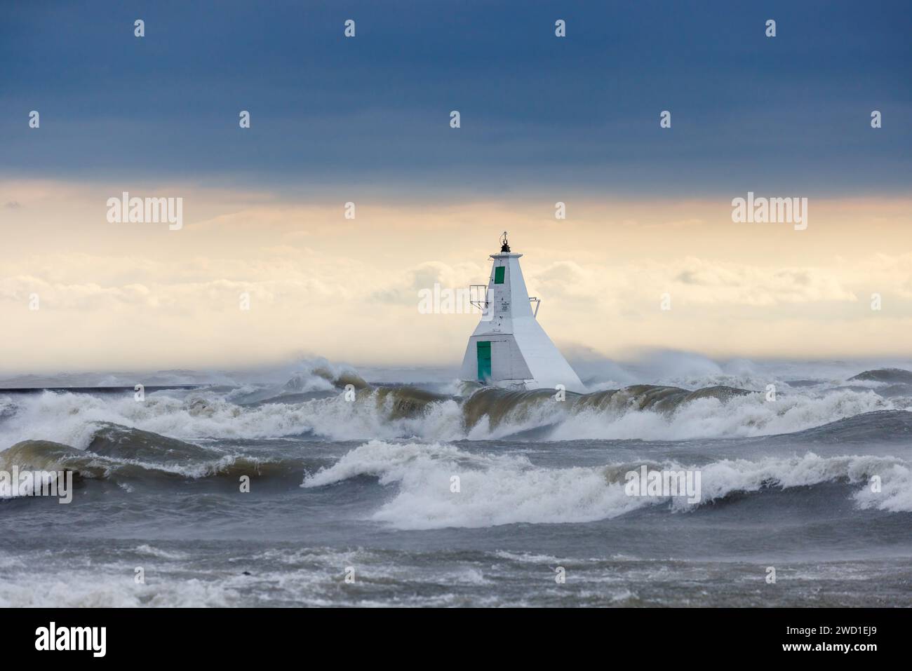 Waves crash before a lighthouse during a breathtaking sunset Stock ...