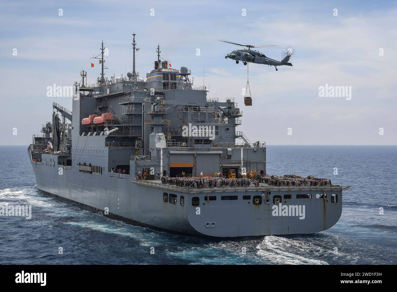 An MH-60S Sea Hawk helicopter transports cargo from USNS Amelia Earhart ...