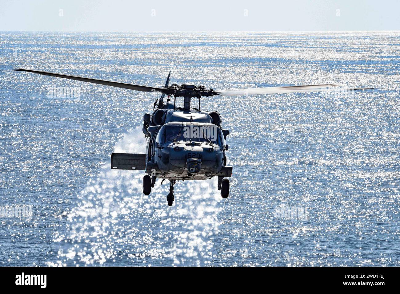 An MH-60S Sea Hawk helicopter flies to the aircraft carrier USS ...